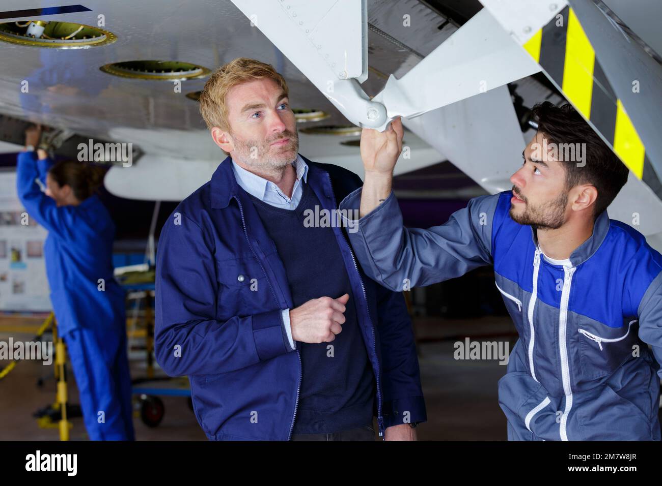 two men working under an airplane Stock Photo - Alamy