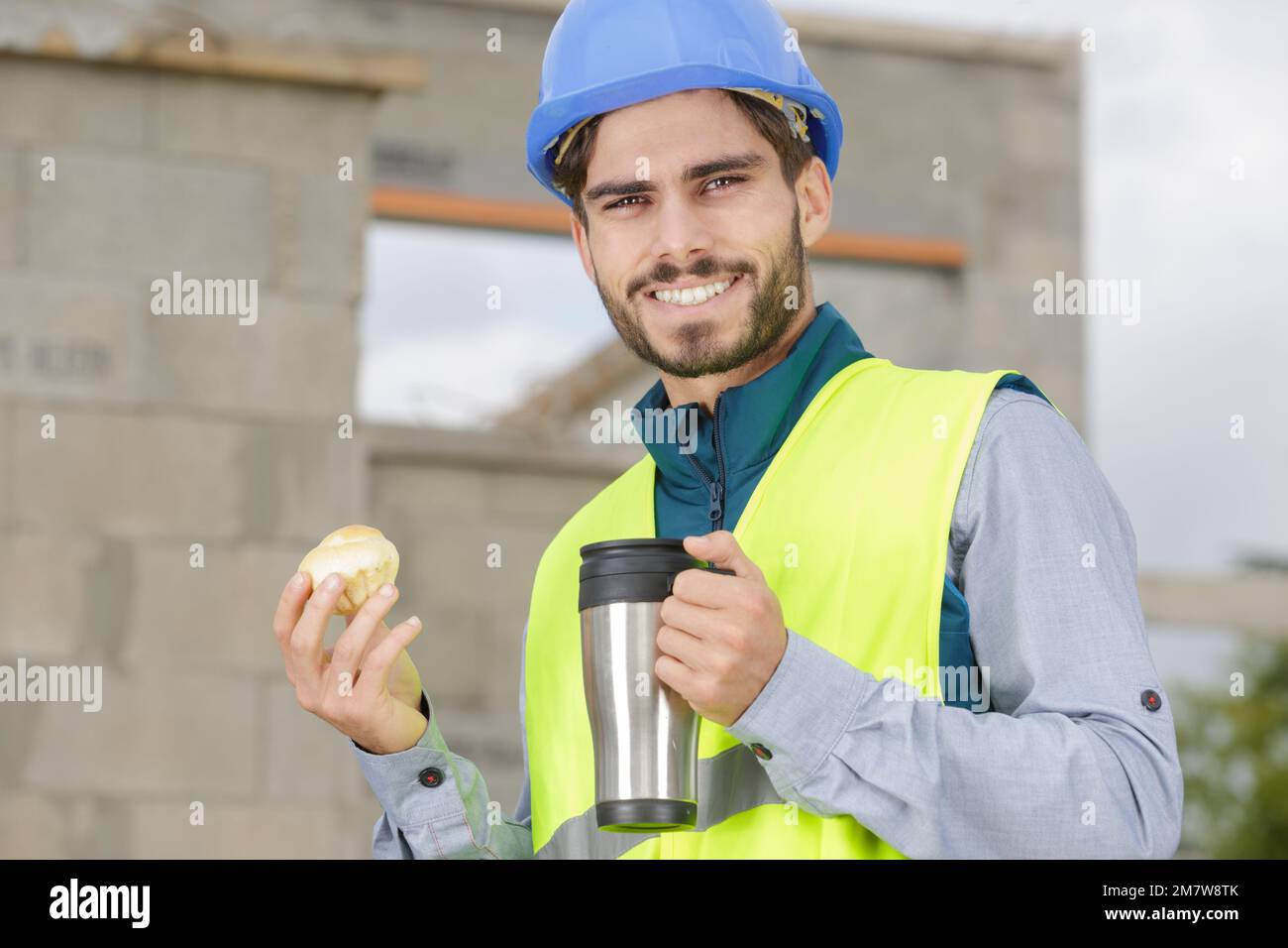 young builder eats a cake and has a coffee Stock Photo - Alamy
