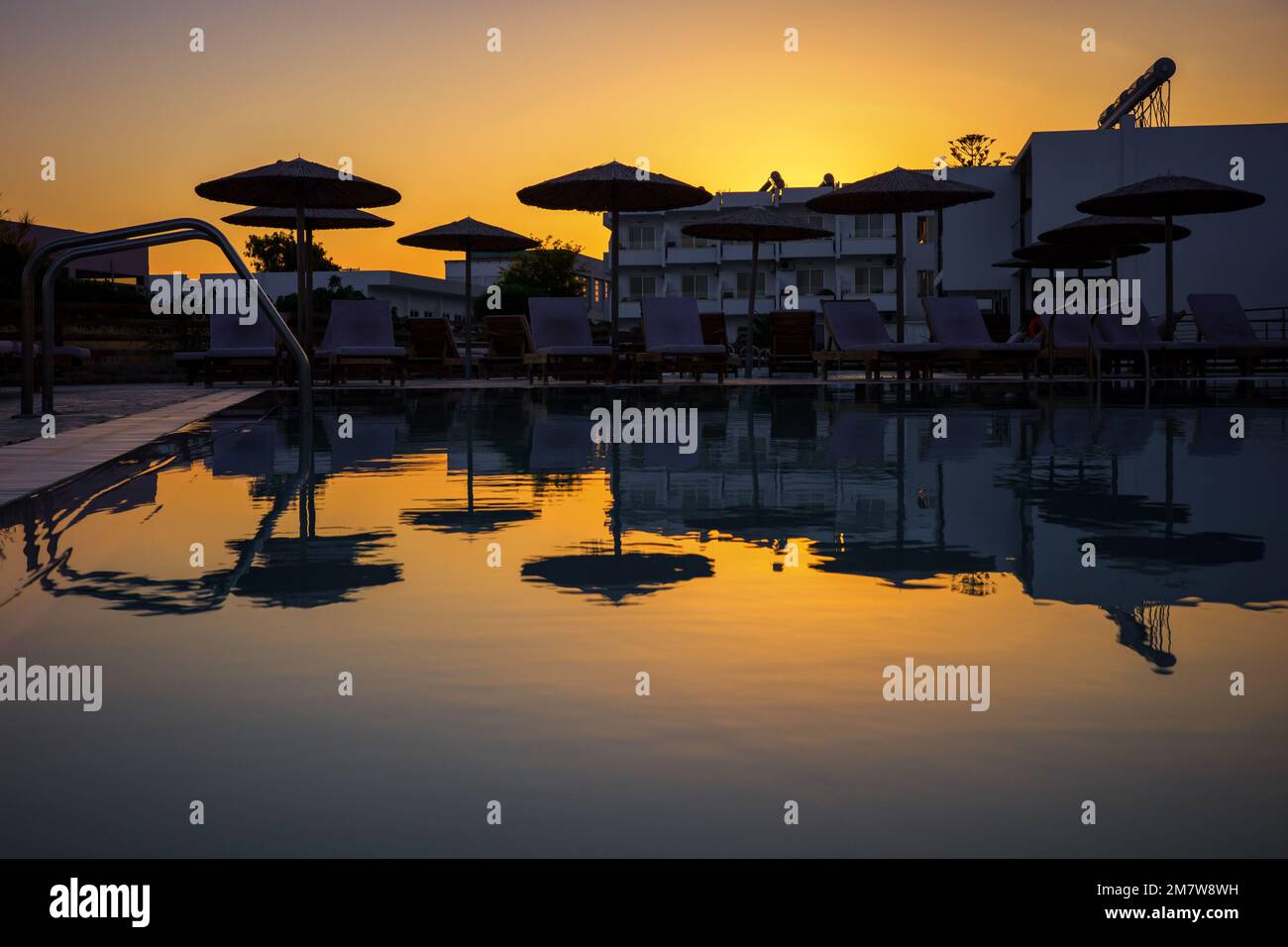 Colorful sky during sunset over empty swimming pool at hotel resort ...