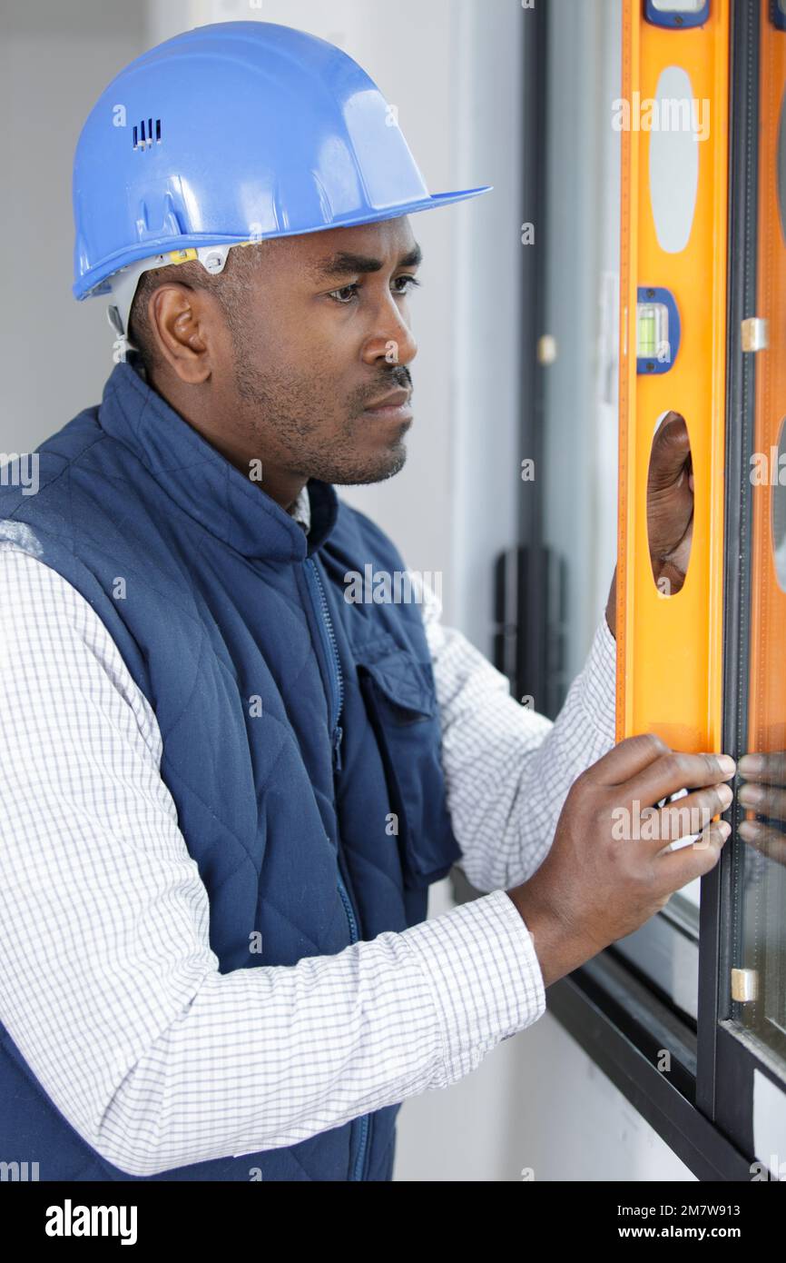 man builder using a level during construction Stock Photo - Alamy