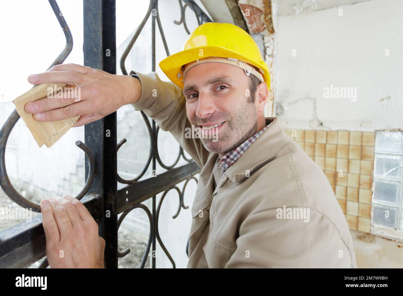 workman using sandpaper on metal window shutters Stock Photo - Alamy