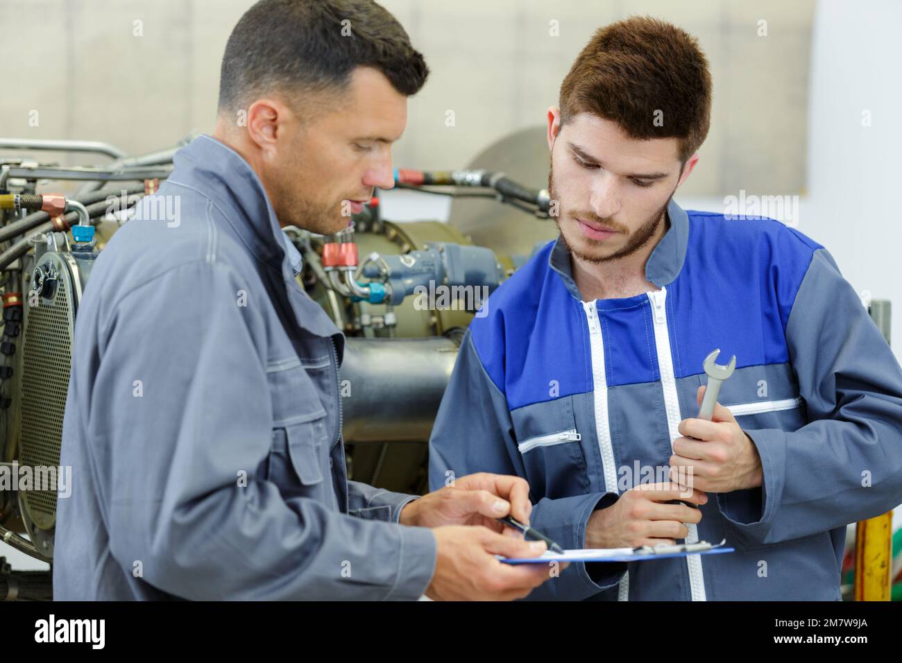 apprentice mechanic and mentor analyzing broken part Stock Photo - Alamy