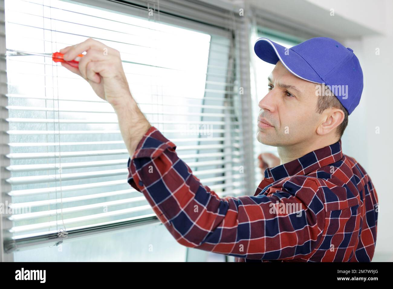 a handyman is screwing the window blinds Stock Photo - Alamy