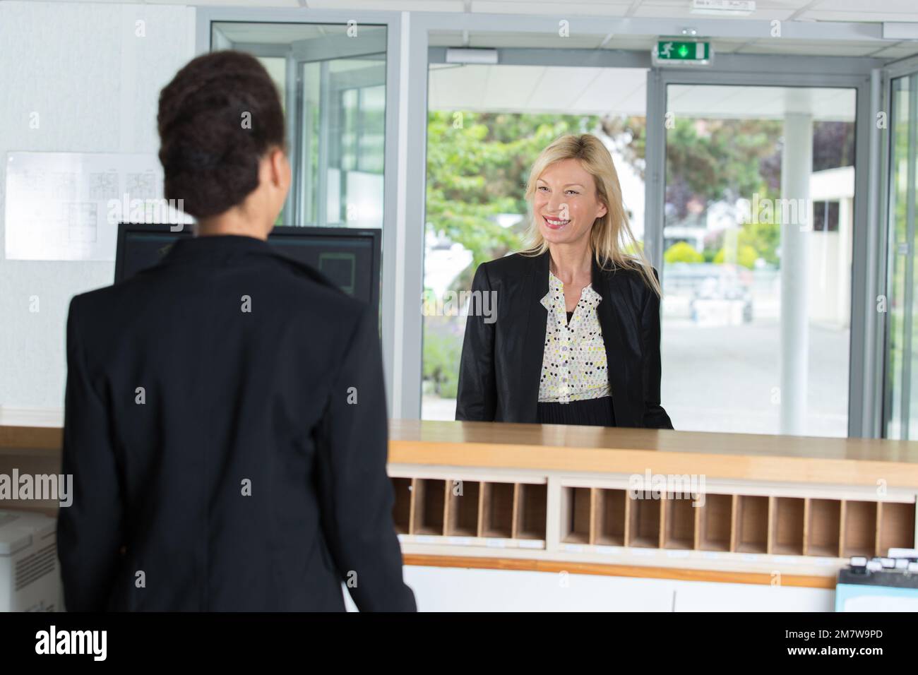 friendly hotel receptionist welcoming female customer Stock Photo - Alamy