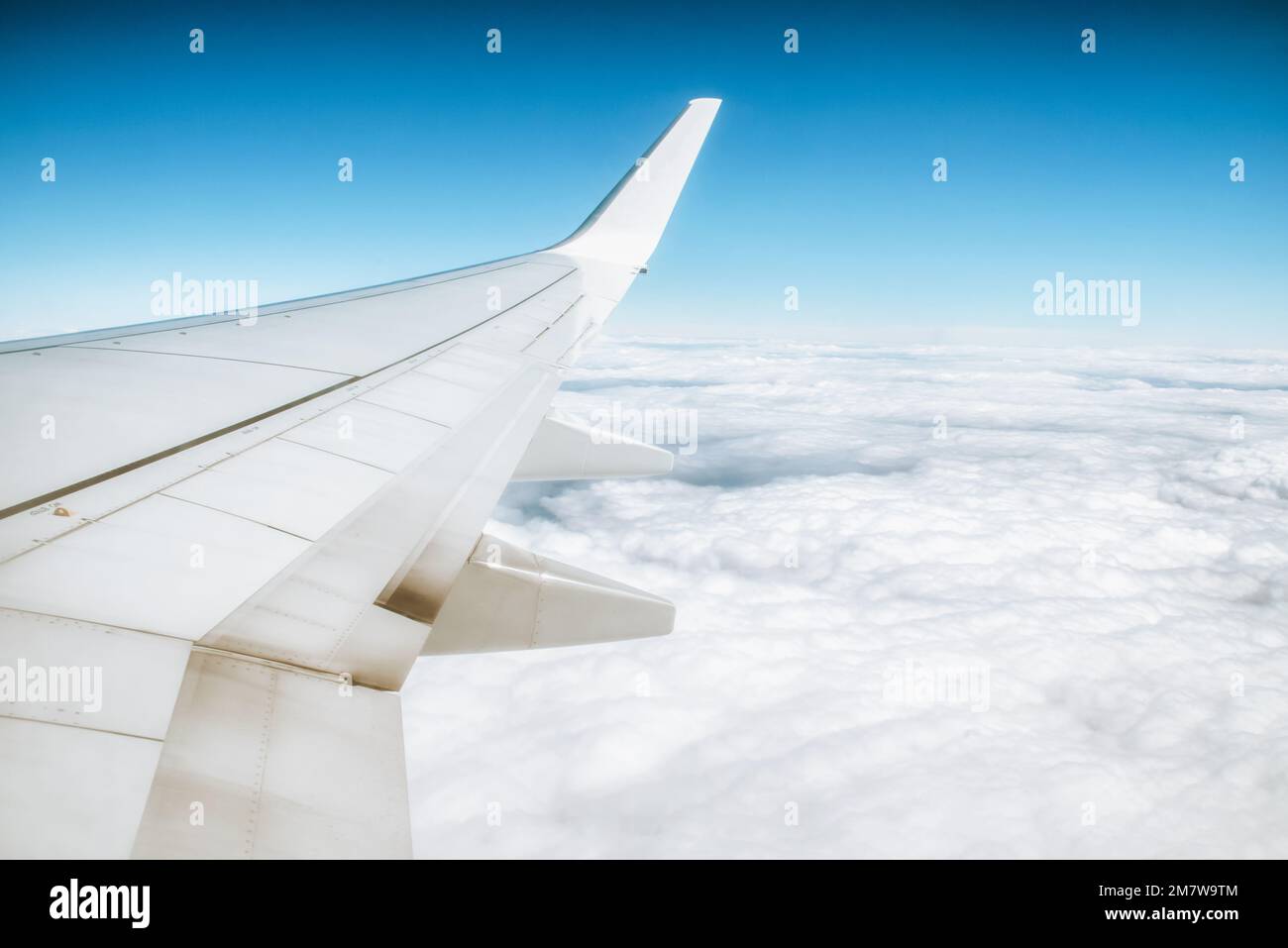 View from window of airplane on sky and clouds under. Flaps on wing of ...