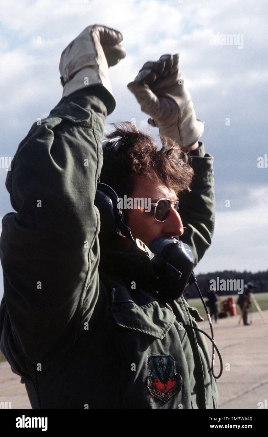 A ground technician marshals an F-16 Fighting Falcon aircraft into a ...