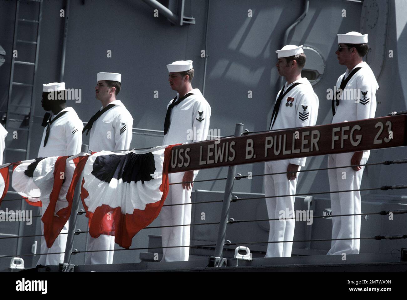 Crewmen line the rails of the guided missile frigate USS LEWIS B ...
