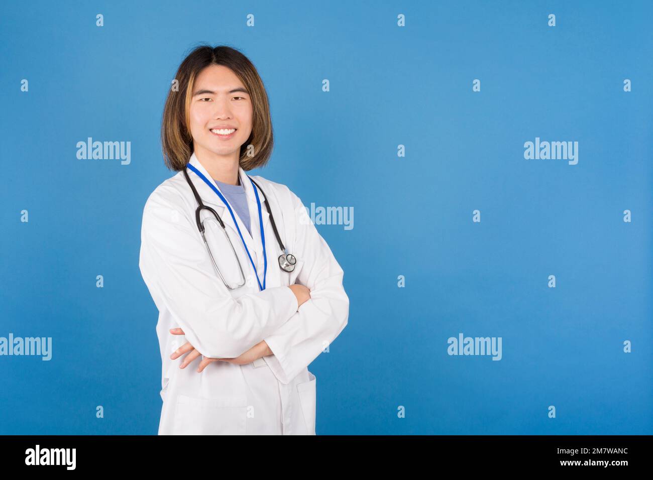 Studio portrait with blue background of an asian doctor smiling at the ...