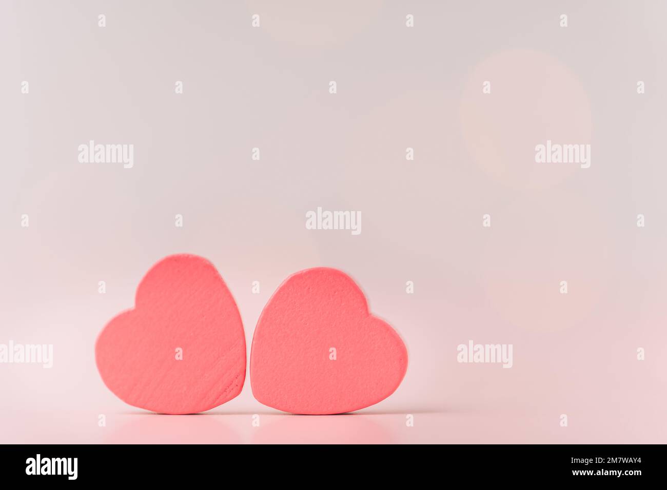 Two red hearts against blurred pink background Stock Photo - Alamy