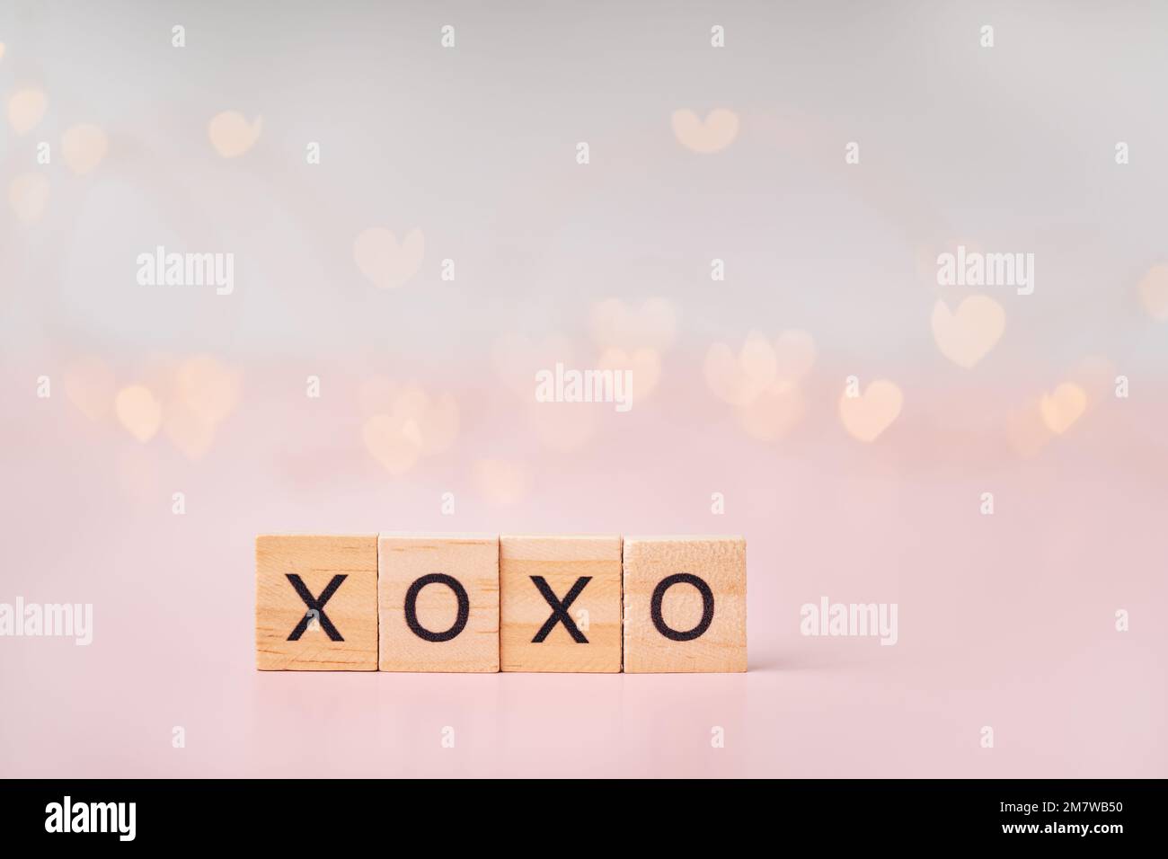 Word love is lined with wooden letters against blurred pink background ...