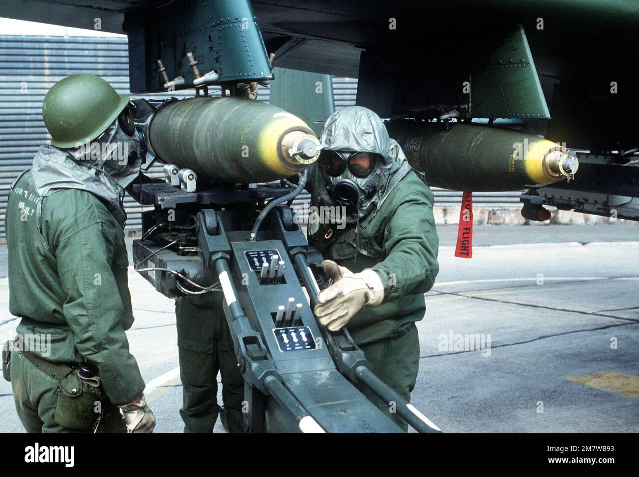 Ground crewmen, in chemical warfare gear, load an Mark 82 bombs onto ...
