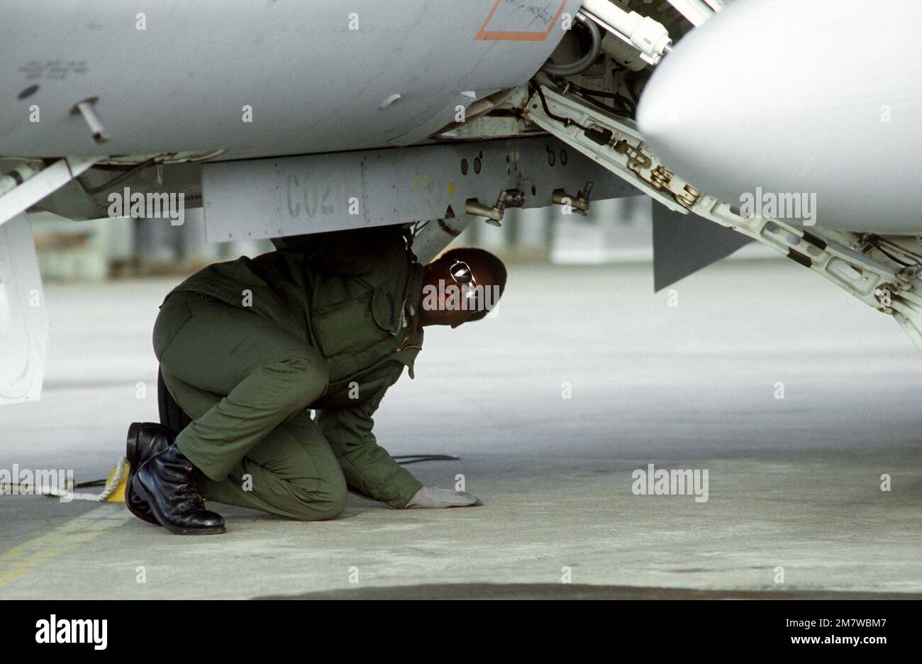 A ground crewman performs maintenance on an F-15 Fighting Falcon ...