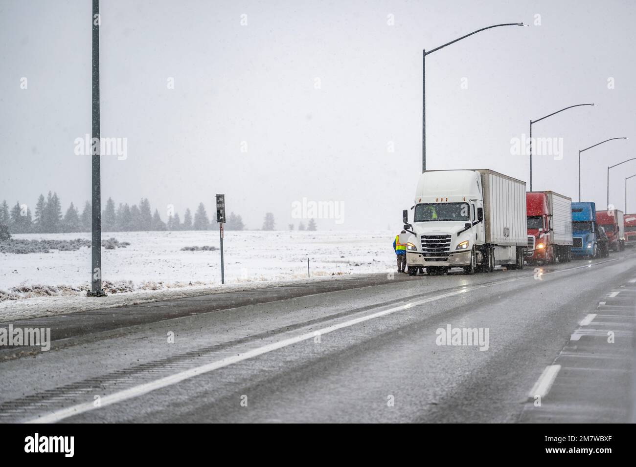 Professional truck driver is installing chains on semi truck standing ...
