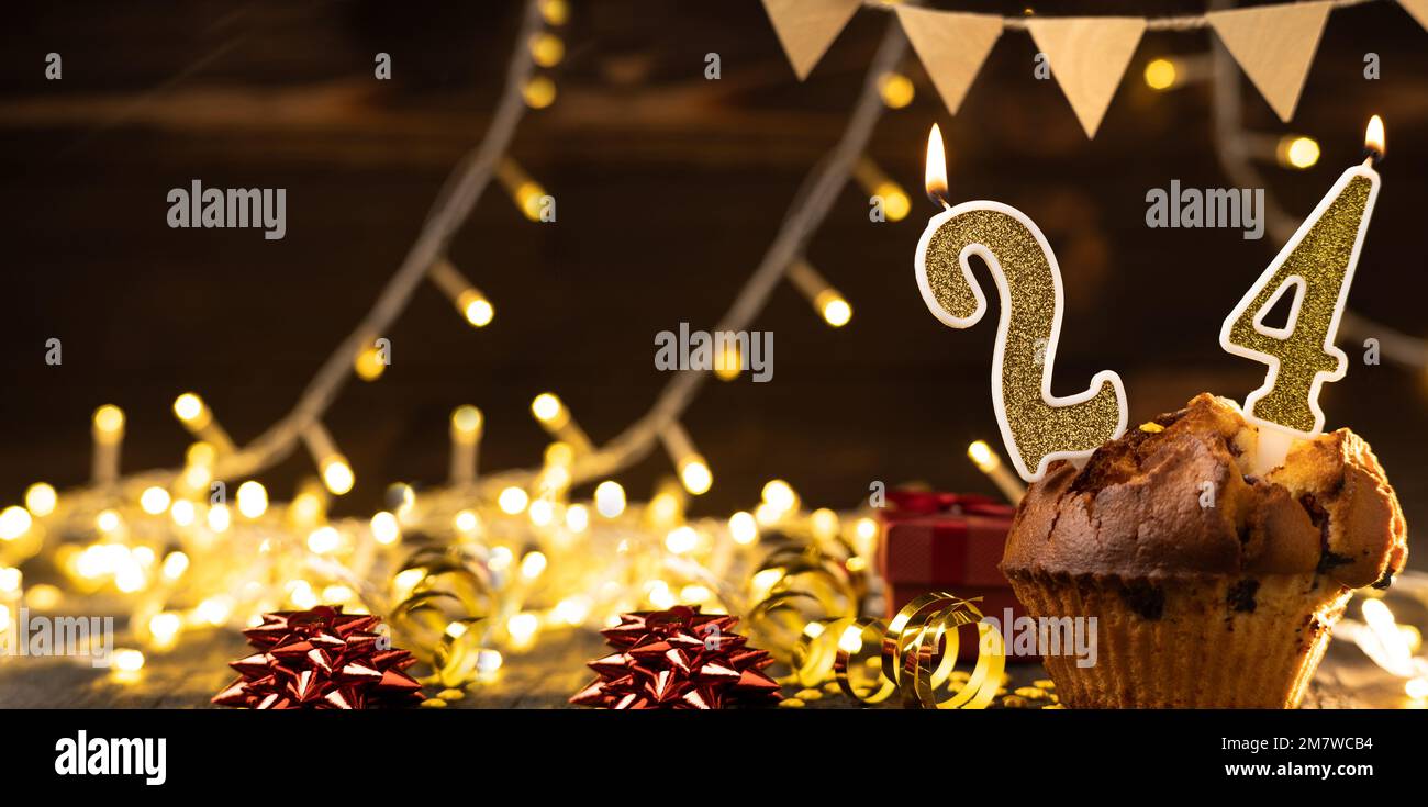 Number 24 gold burning candle in a cupcake against celebration wooden ...
