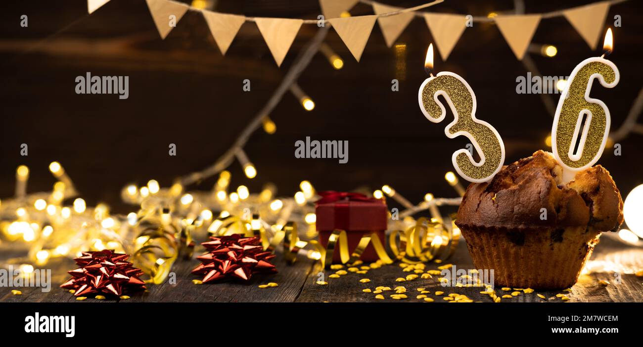 Number 36 birthday celebration candle in cupcake against lights and ...