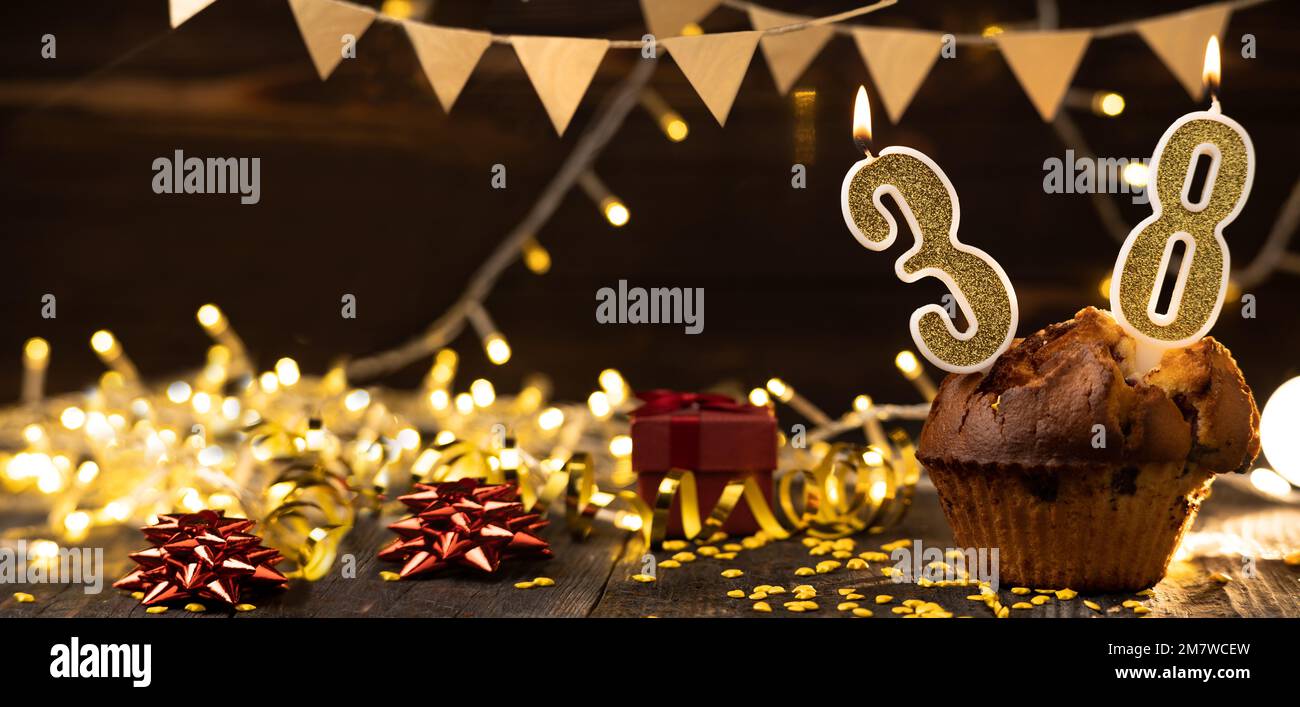 Number 38 birthday celebration candle in cupcake against lights and ...