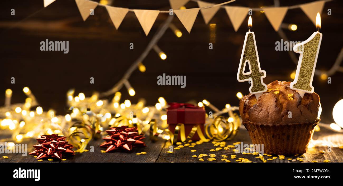 Number 41 birthday celebration candle in cupcake against lights and ...