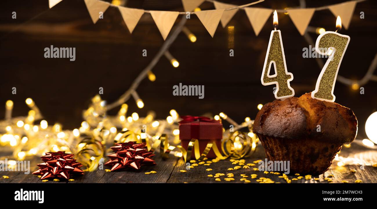 Number 47 golden festive burning candles in a cake, wooden holiday ...