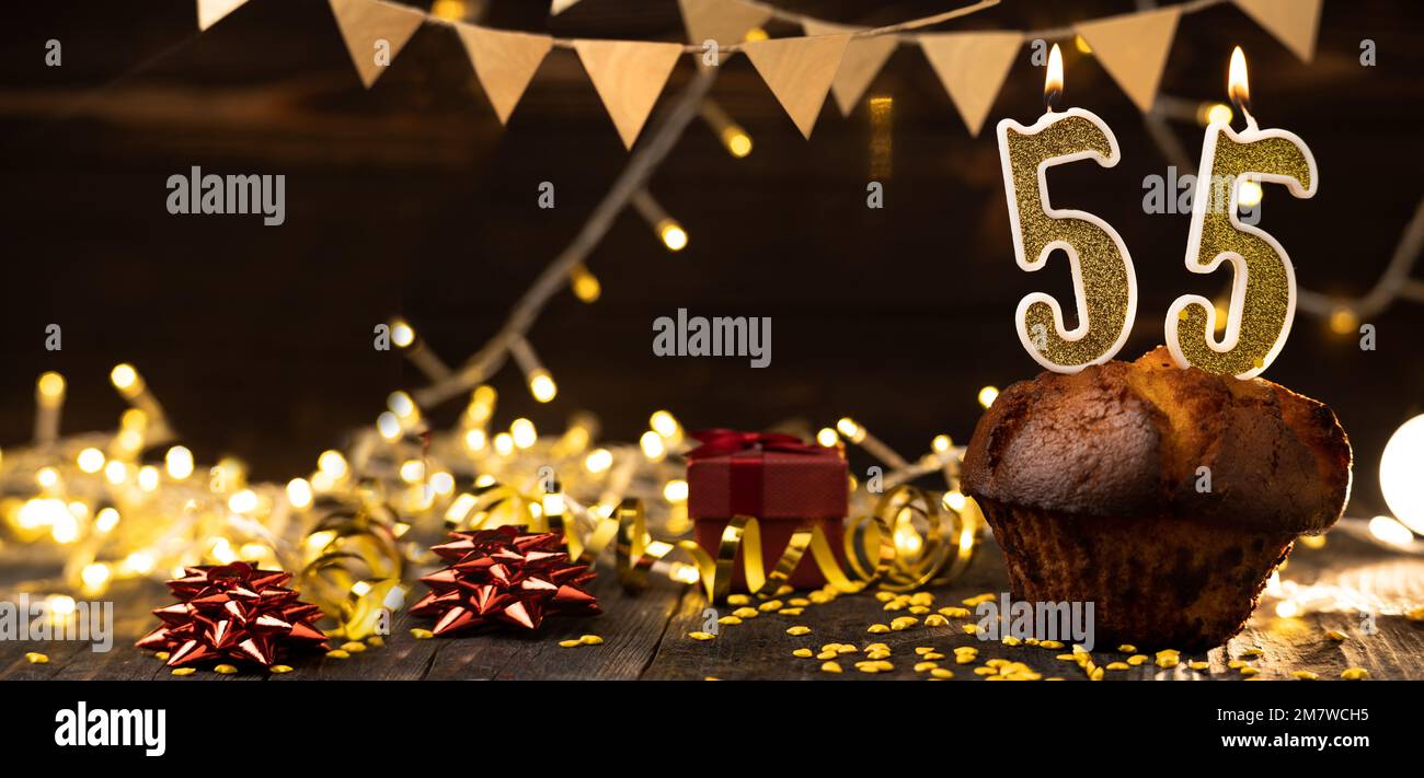 Number 55 golden festive burning candles in a cake, wooden holiday ...