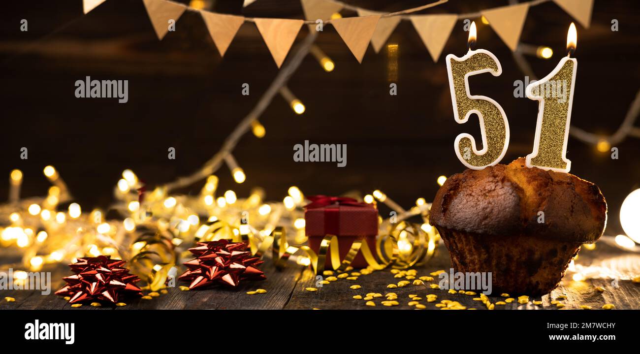 Number 51 golden festive burning candles in a cake, wooden holiday ...