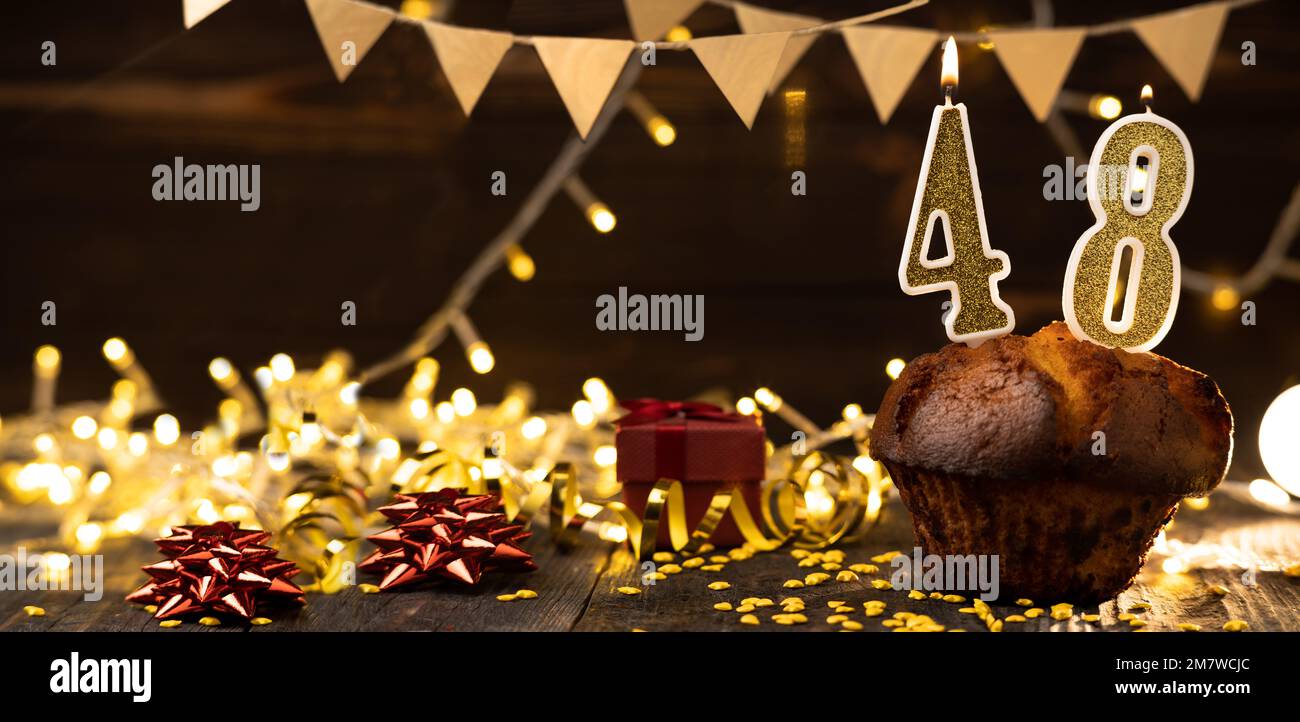 Number 48 golden festive burning candles in a cake, wooden holiday ...