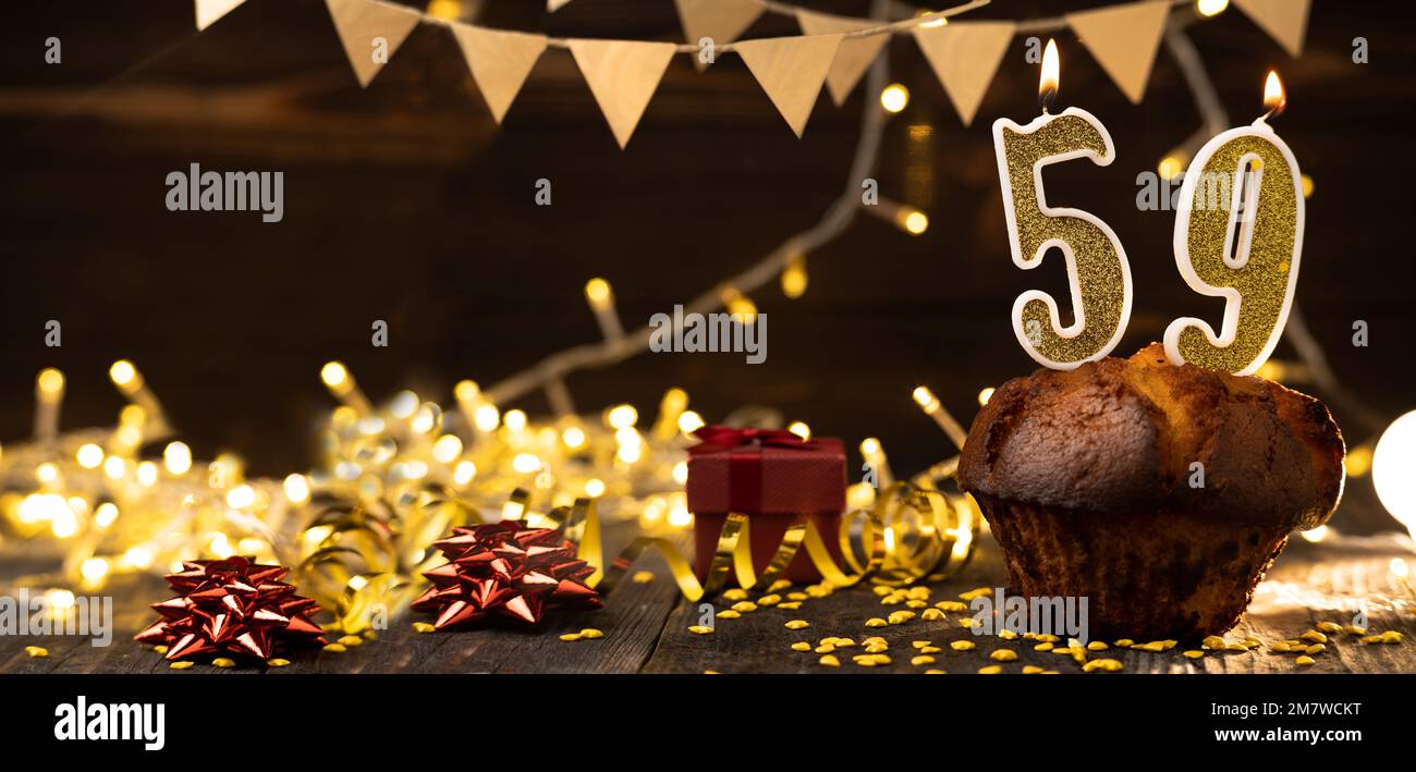 Number 59 golden festive burning candles in a cake, wooden holiday ...