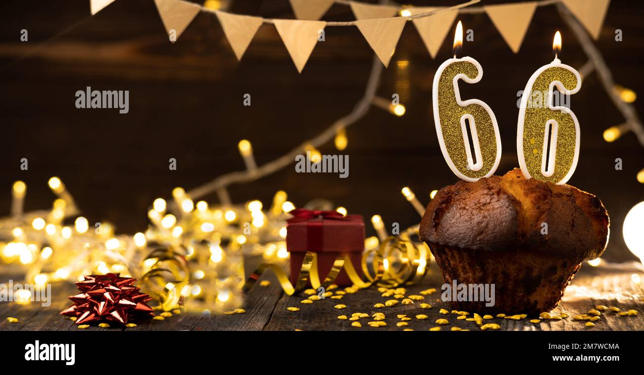 Number 66 golden festive burning candles in cake, wooden holiday ...