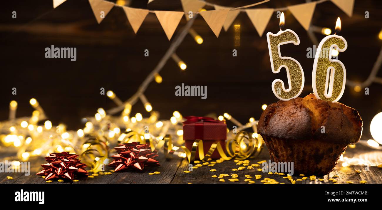 Number 56 golden festive burning candles in a cake, wooden holiday ...