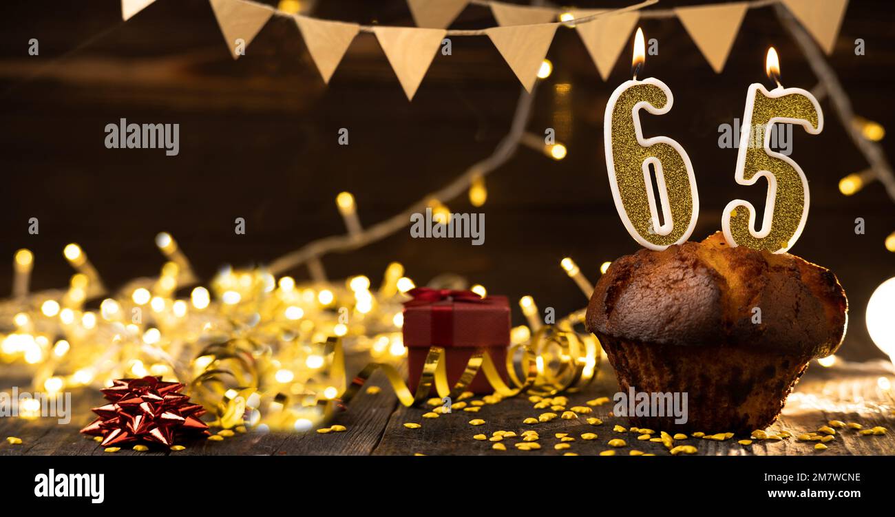 Number 65 golden festive burning candles in a cake, wooden holiday ...