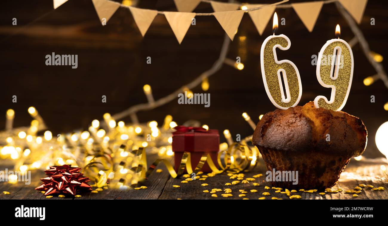 Number 69 golden festive burning candles in a cake, wooden holiday ...