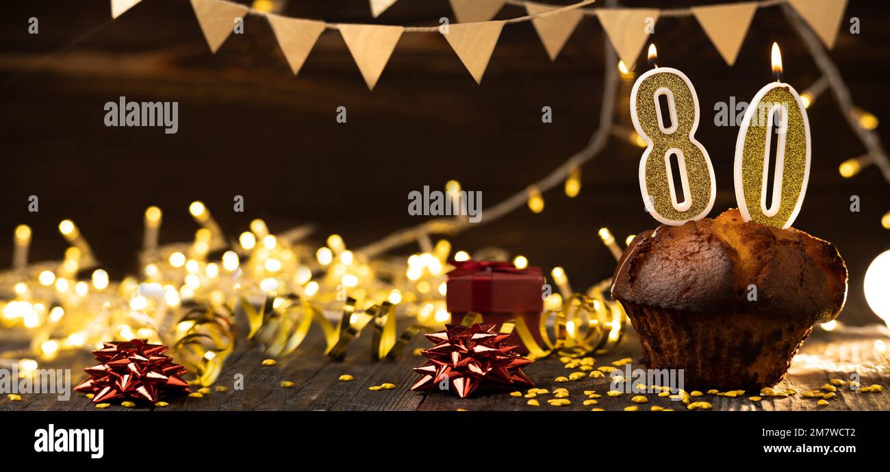 Number 80 golden festive burning candles in a cake, wooden holiday ...