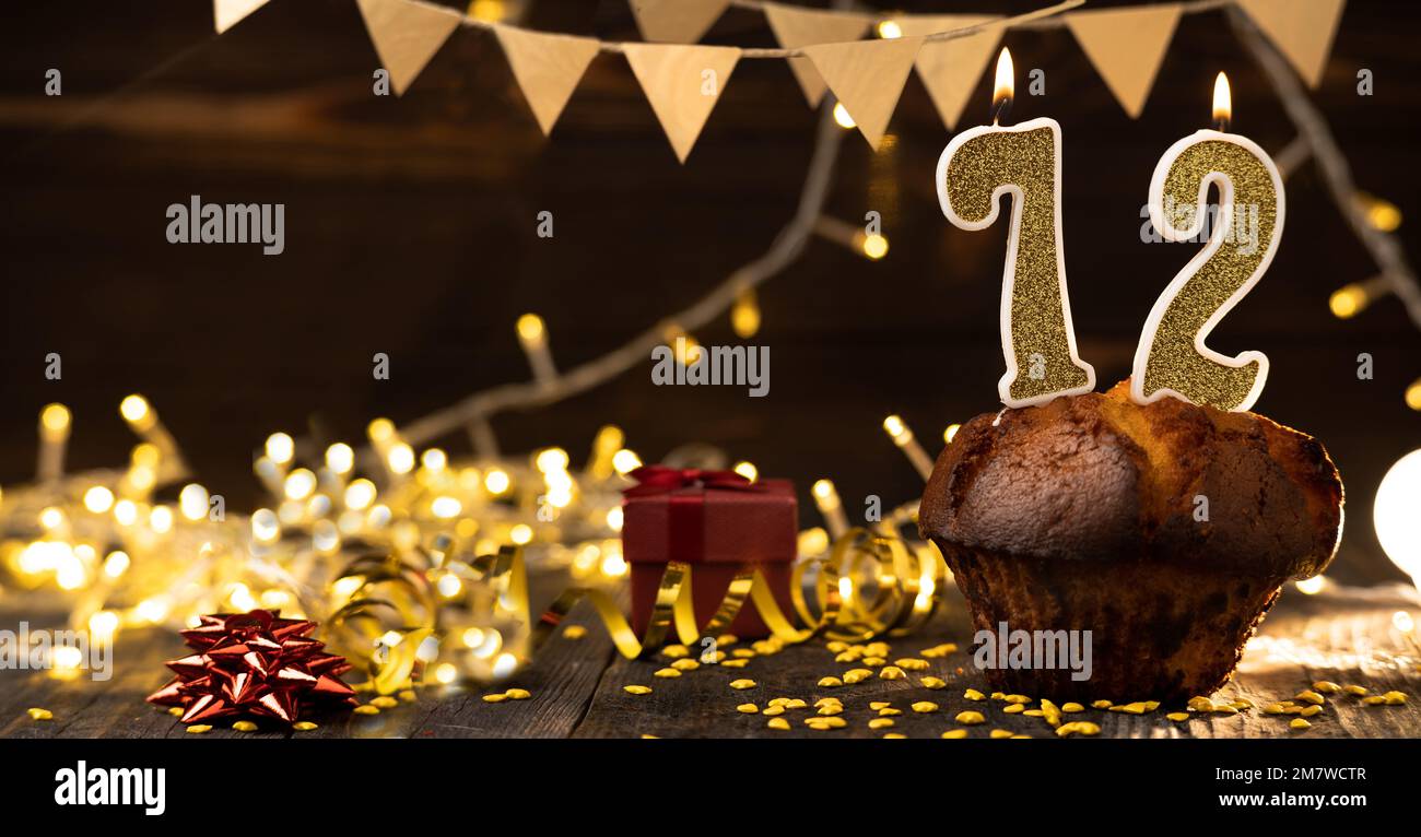 Number 72 golden festive burning candles in a cake, wooden holiday ...