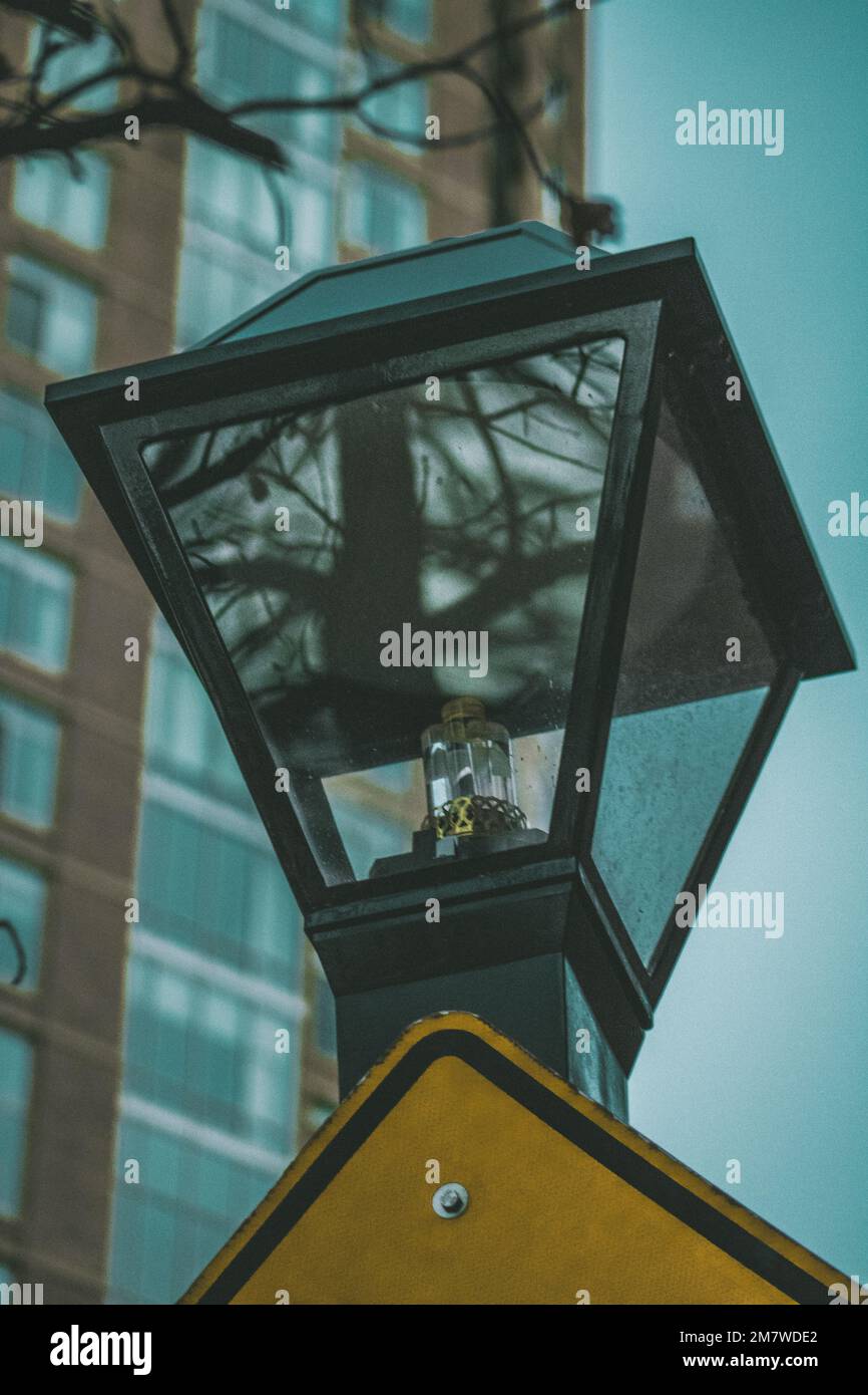 A vertical closeup of a street lantern, lamp post captured in a street ...