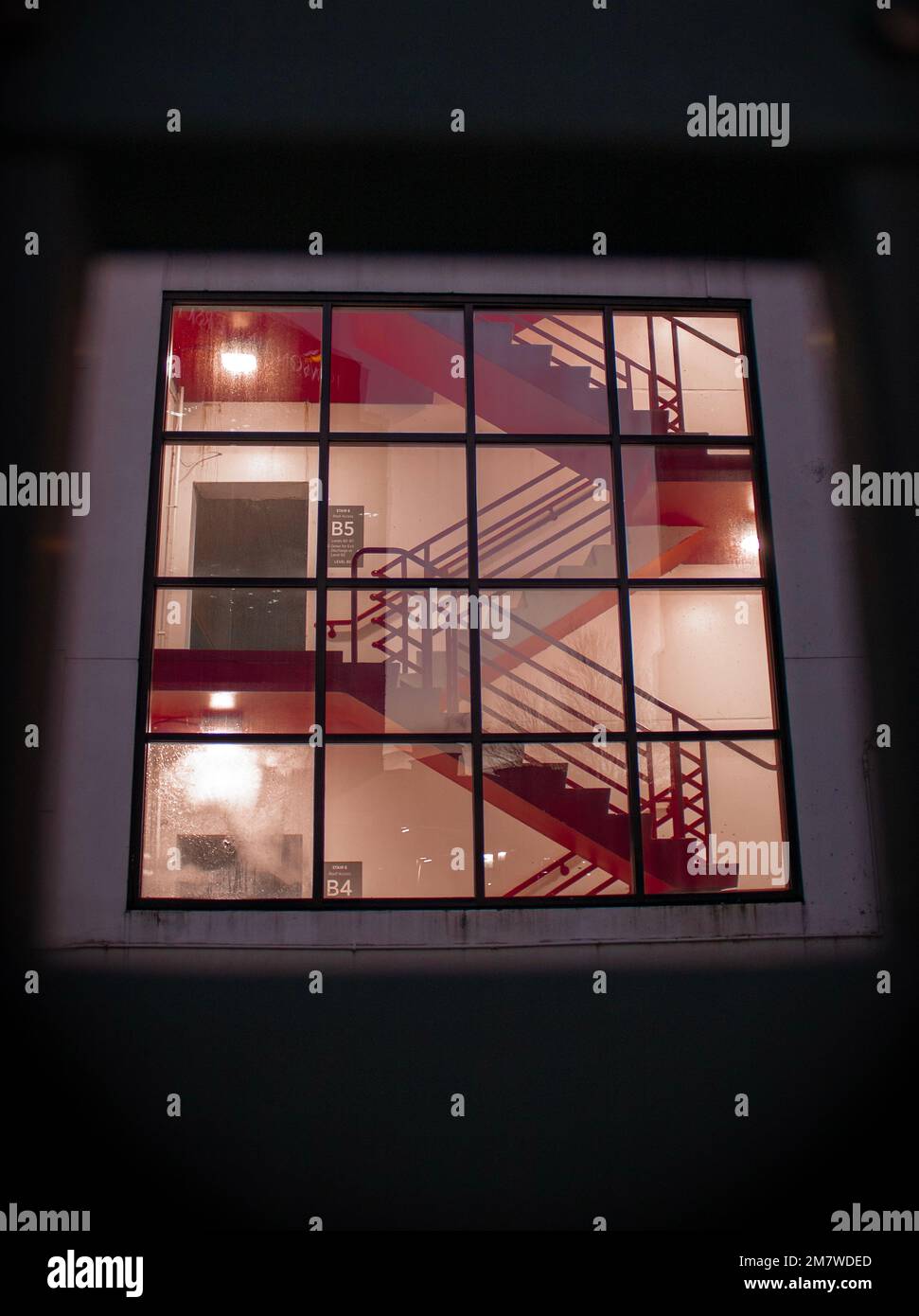 A vertical of red stairs, stairways seen from a square window with ...