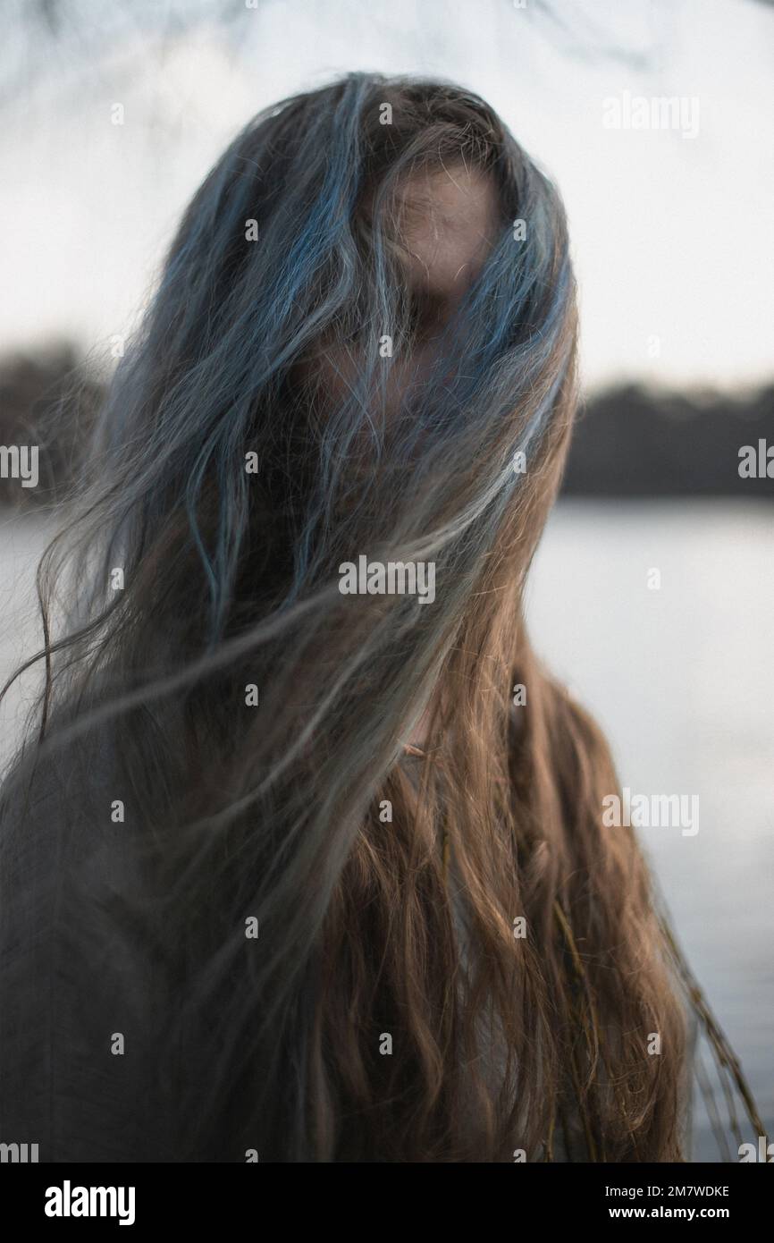 Close up long gray brown hair hiding woman face with wind portrait ...