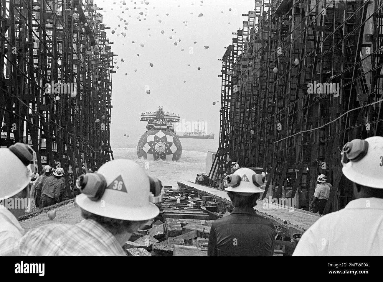 Shipyard workers, standing beneath the scaffolding, watch the nuclear ...