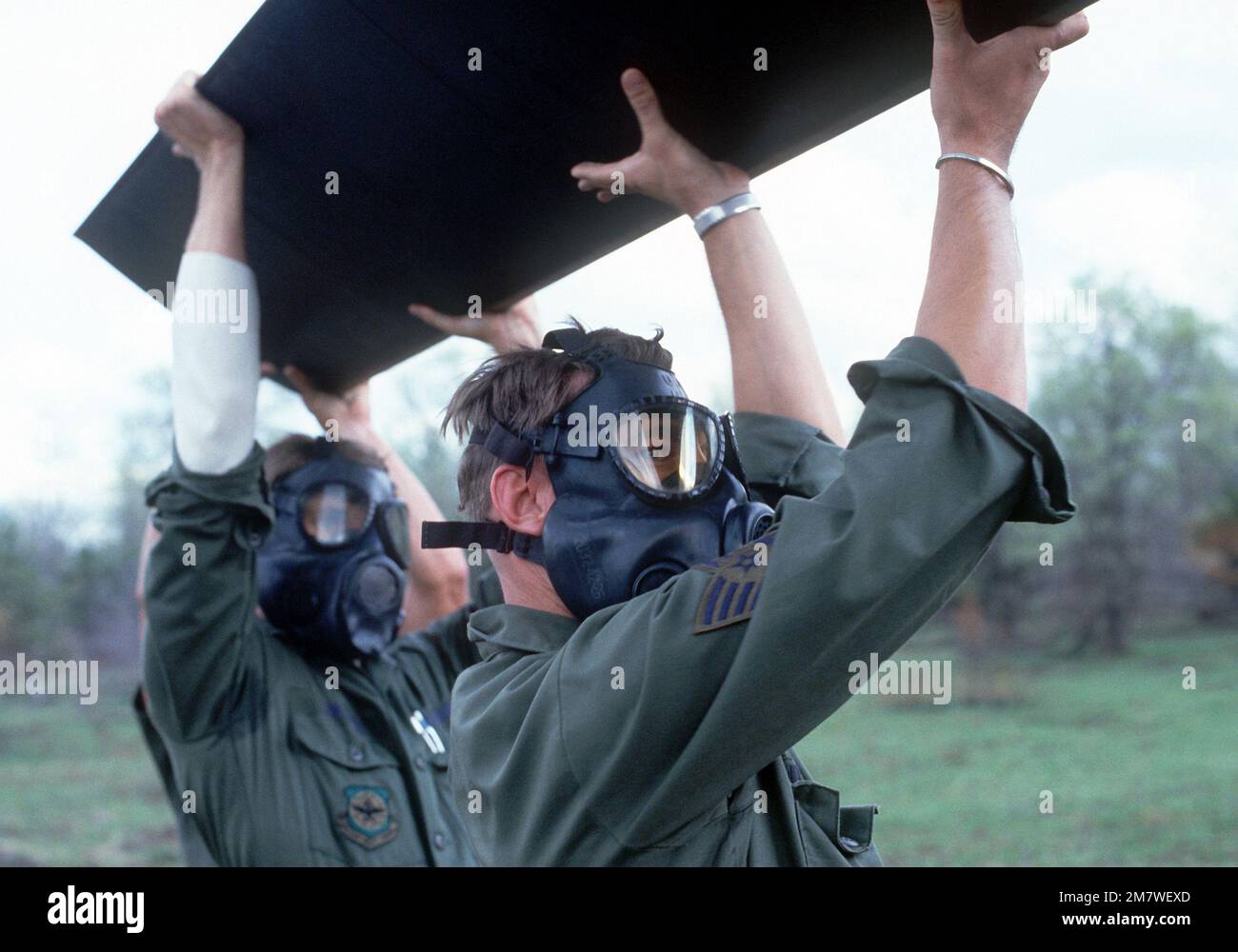 Crew members wearing gas masks, replace a rotor blade on an HH-3E Jolly ...