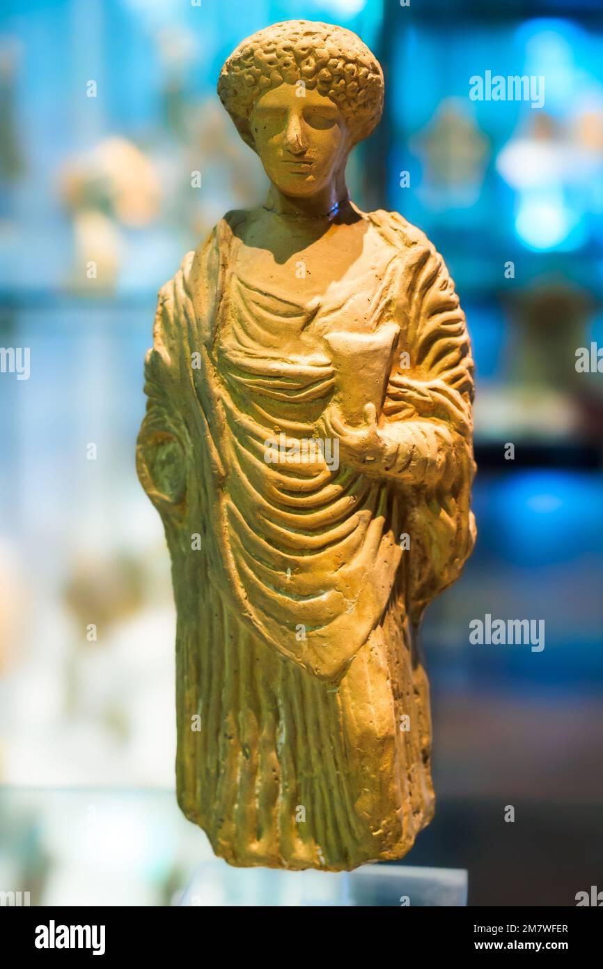 Figure of a woman holding a vase on her arms folded across her chest ...