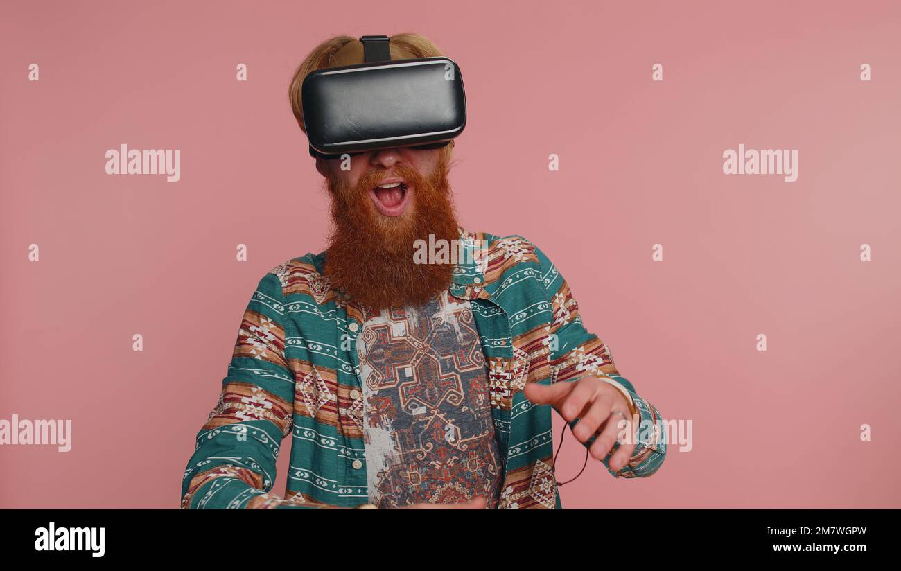 Redhead bearded hippie man using headset helmet app to play simulation ...