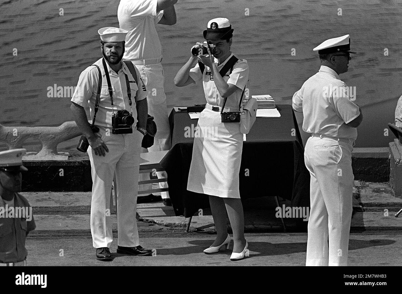 A Navy photographer takes pictures of the ceremony marking the ...