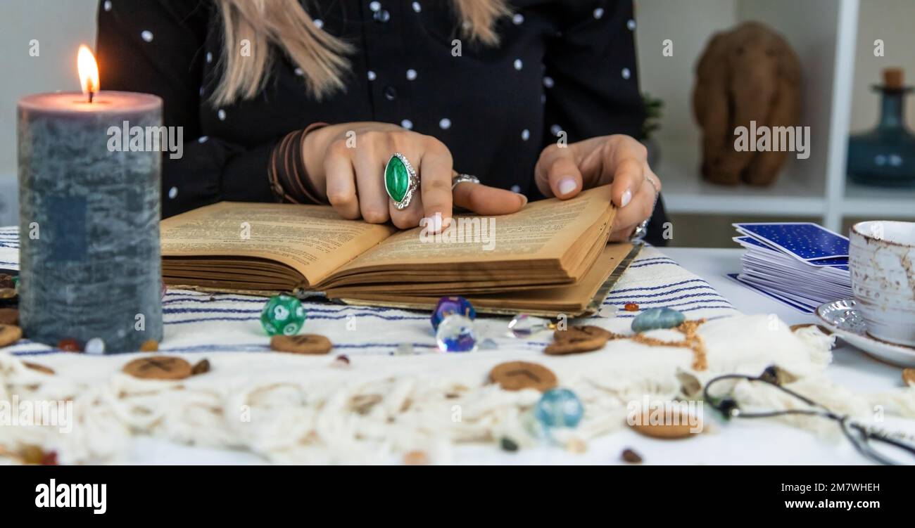 Woman fortune teller reads a book of spells. Selective focus. People ...