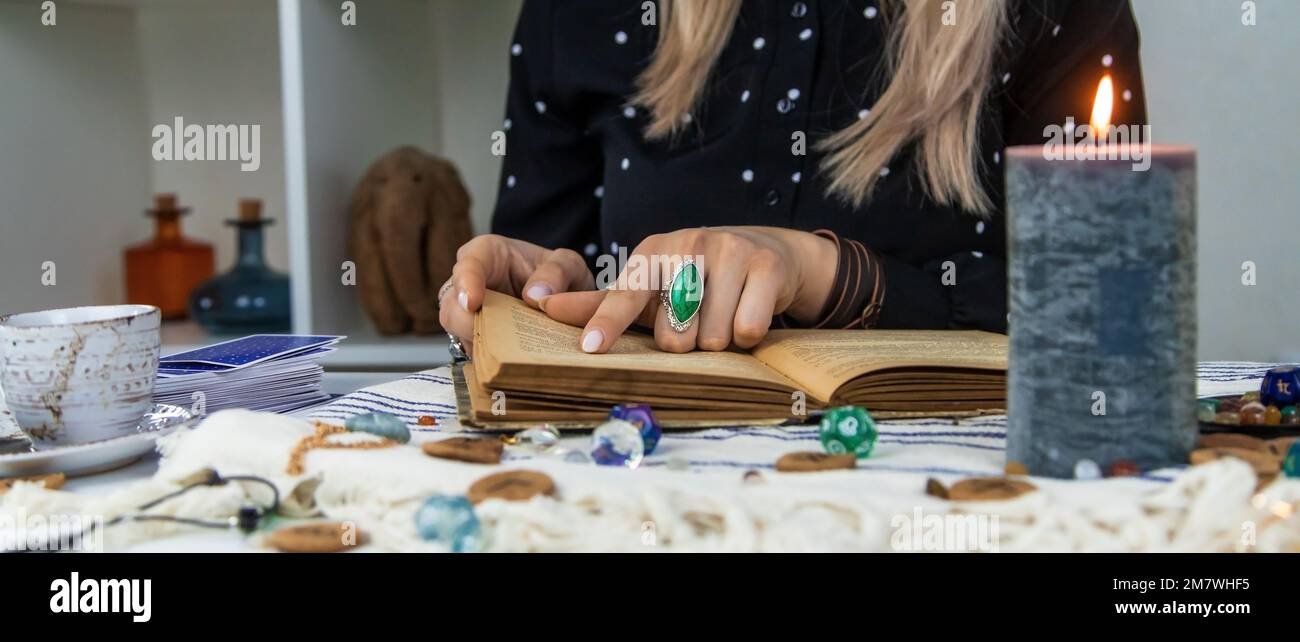 Woman fortune teller reads a book of spells. Selective focus. People ...