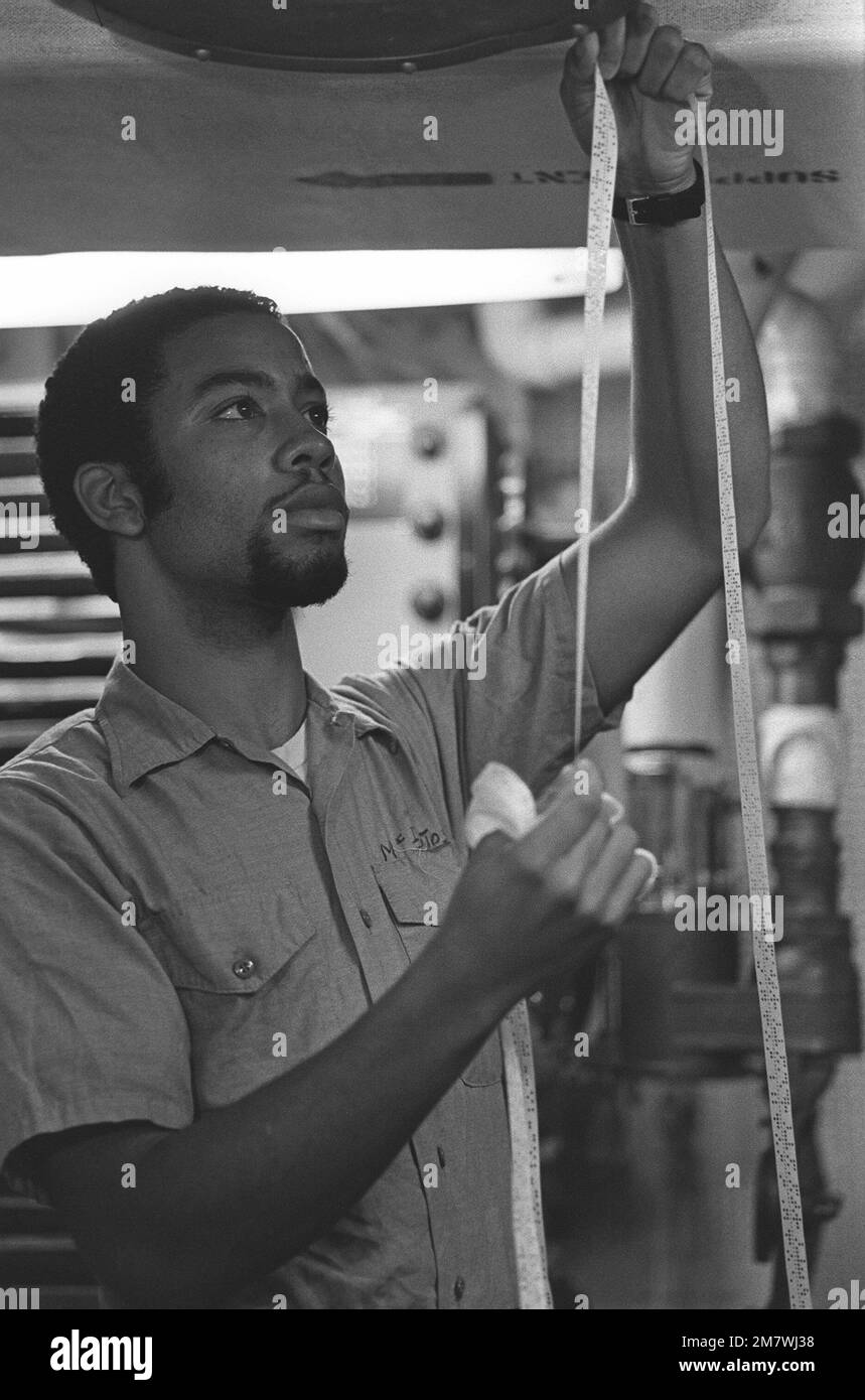 Radioman Wayne McIntosh checks a perforated tape in the radio central ...