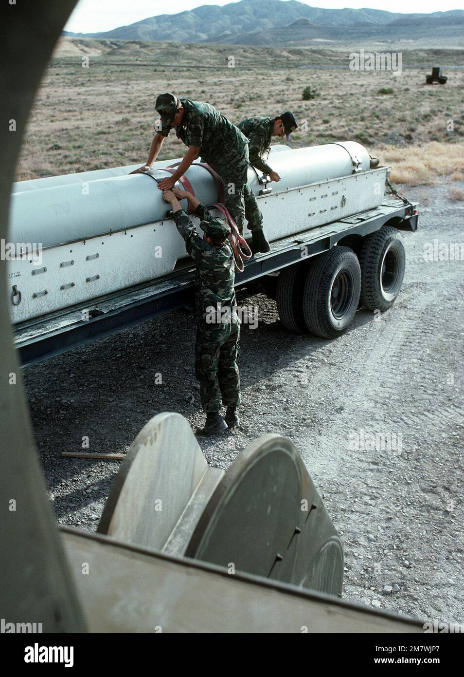 Air Force personnel secure an empty missile canister on a trailer truck ...