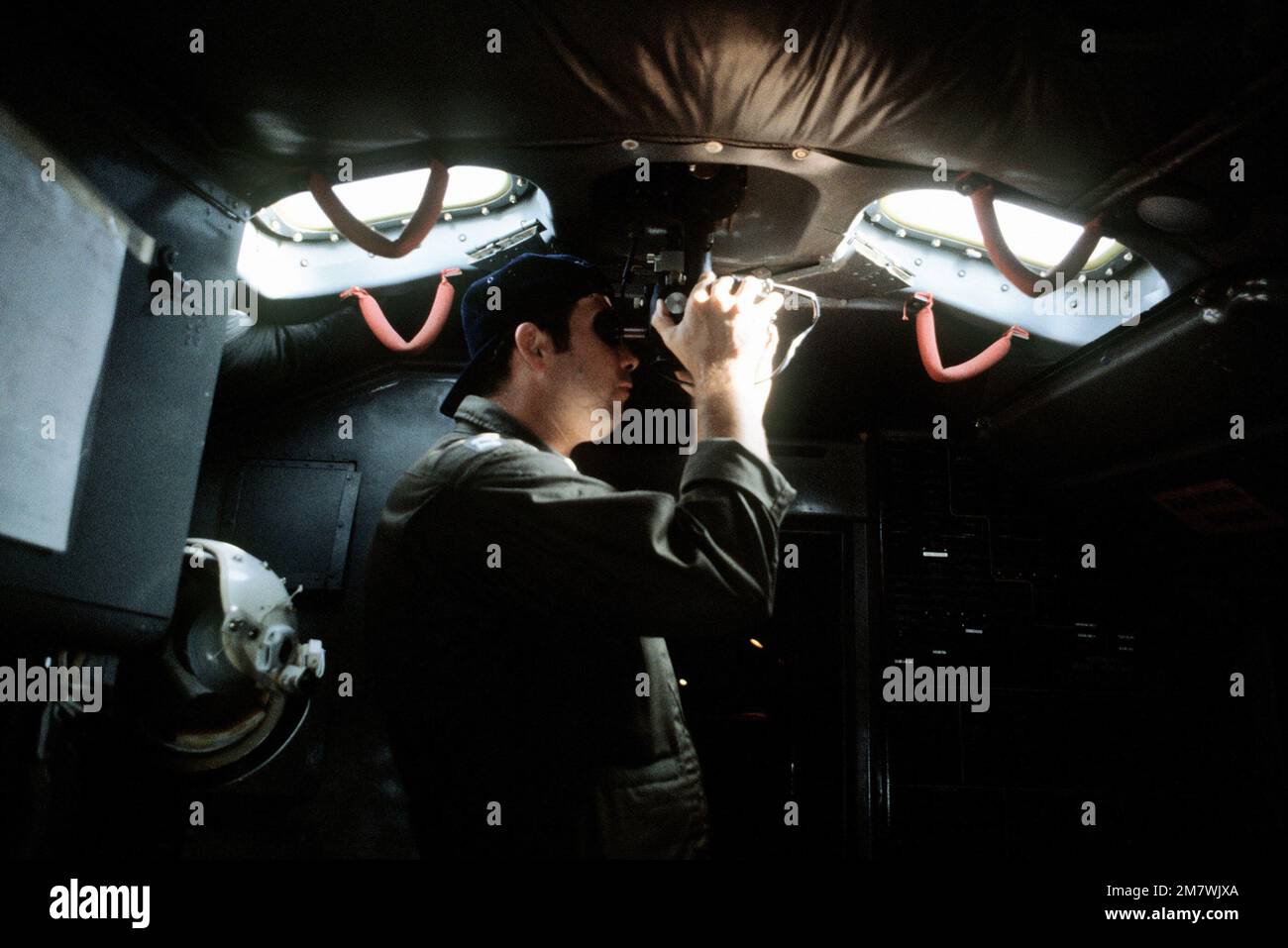 A navigator aboard a KC-135 Stratotanker aircraft operates a sextant ...
