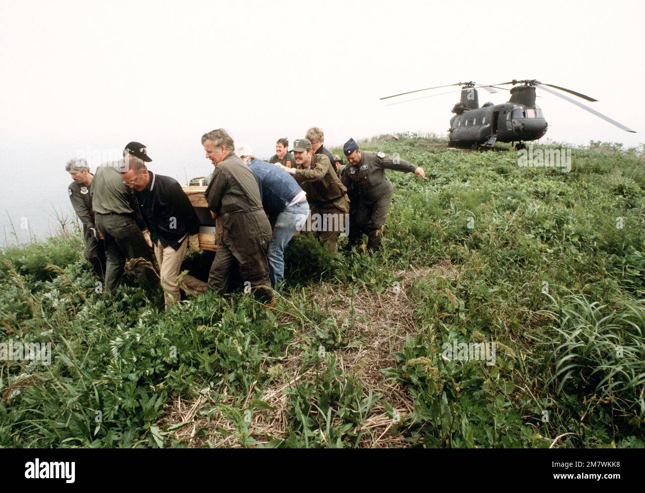 Crewmen carry a pallet of batteries away from a CH-47B Chinook ...