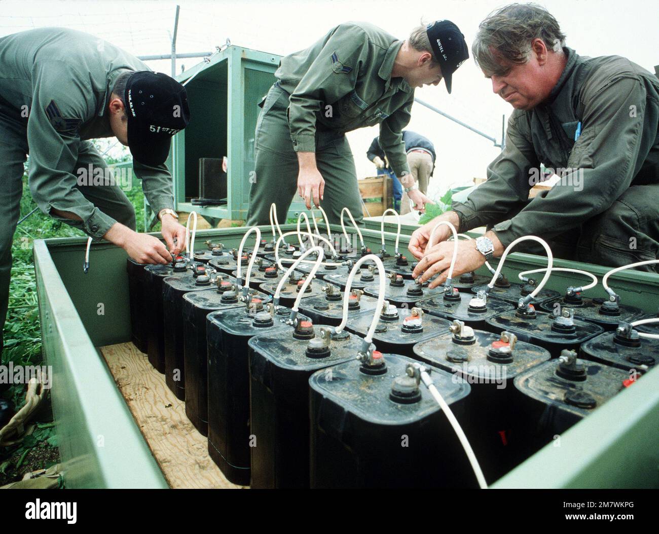 Crewmen check and tighten the connection on batteries being used for ...