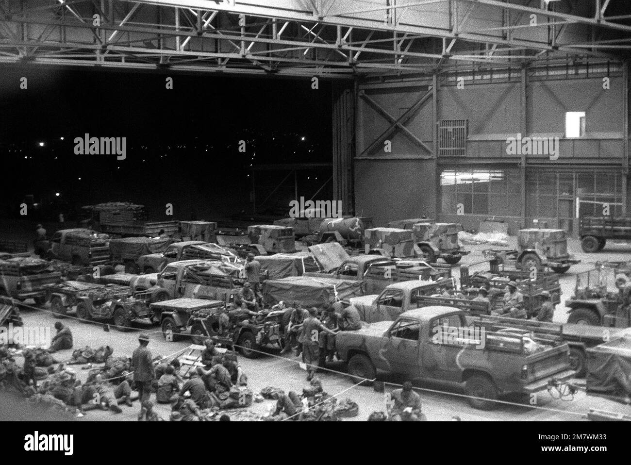 Personnel await their turn to load their equipment onto an aircraft as ...