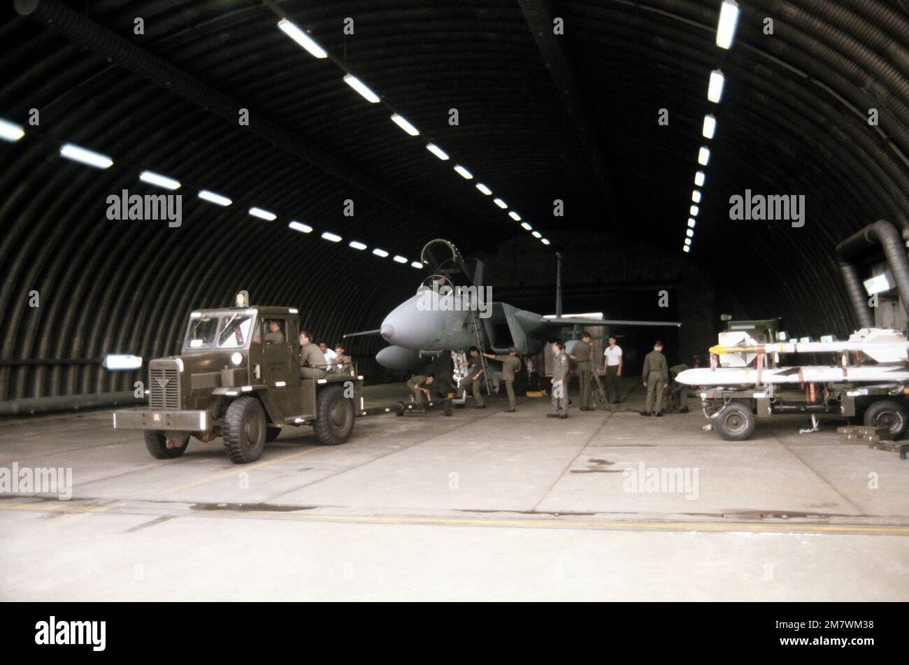 A ground crew rolls an F-15A Eagle aircraft into a tab-vee shelter for ...