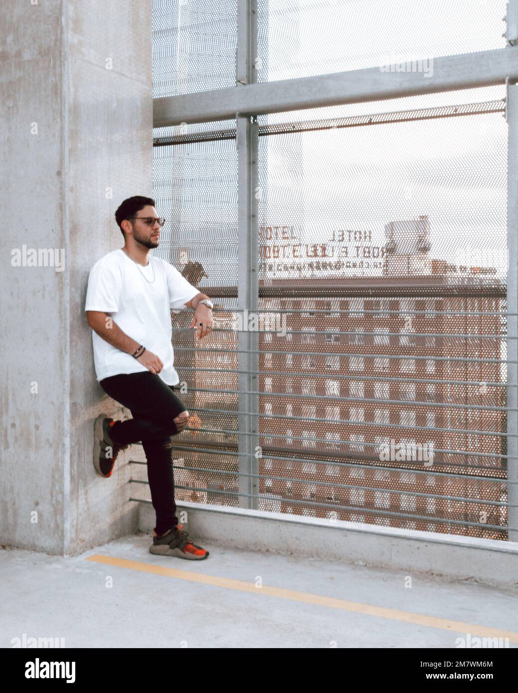 A young guy standing outside behind the window with the city in the ...